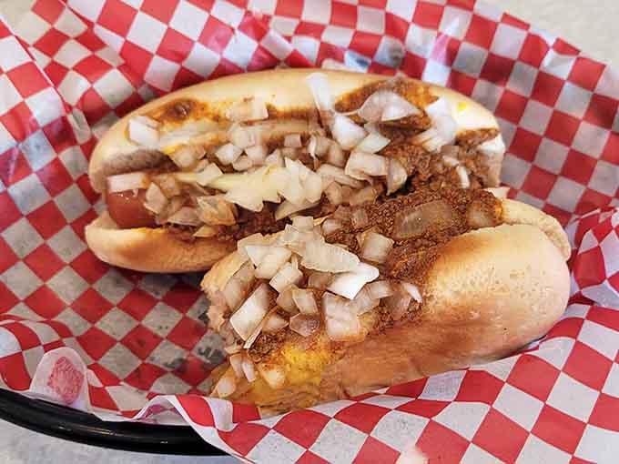 Two perfectly griddled hot dogs nestled in buns, topped with enough onions to keep vampires away for weeks.