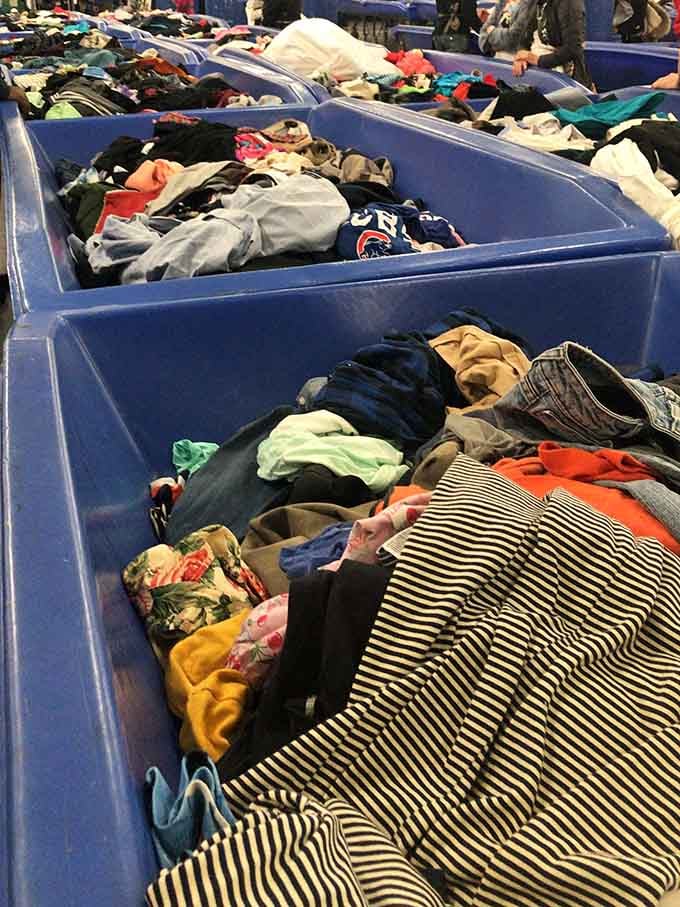 Striped shirts and colorful fabrics cascade through bins like a textile waterfall waiting for someone to dive in.
