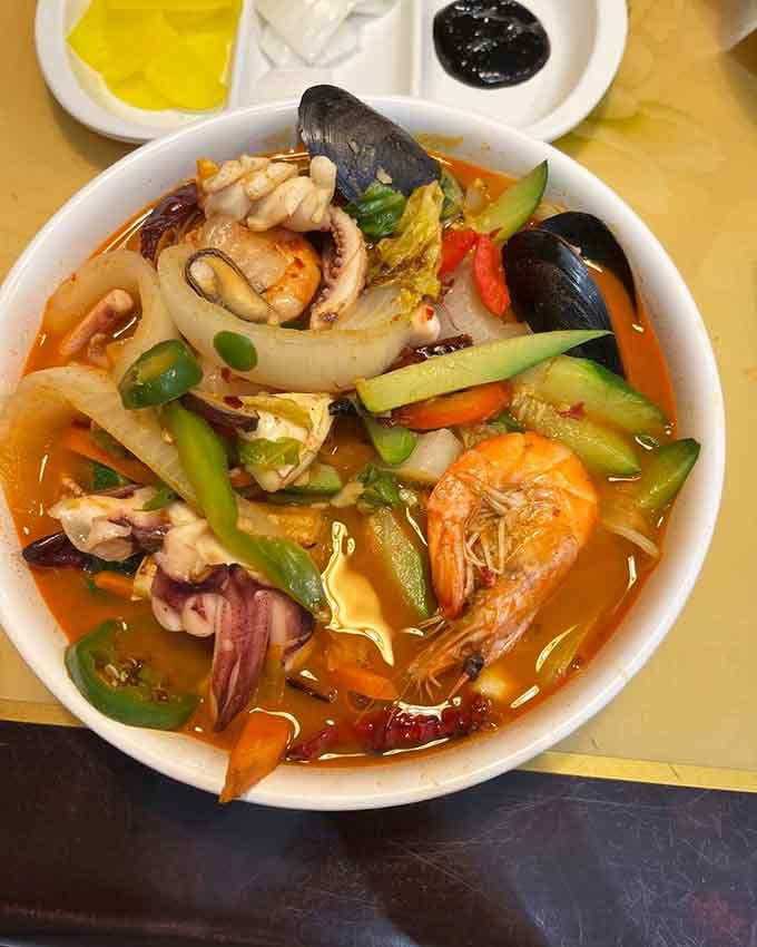 Spicy seafood soup so vibrant it practically glows, packed with ocean treasures swimming in fiery, flavorful broth.