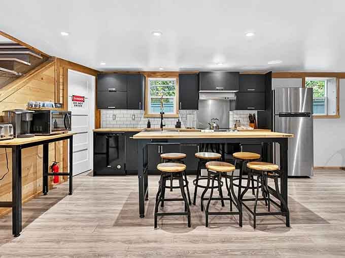 That sleek black kitchen with butcher block counters and bar seating makes meal prep feel like catering at Jurassic Park.