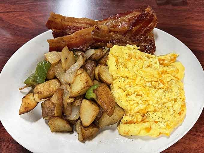 Crispy bacon stands at attention next to perfectly seasoned home fries and fluffy eggs, a plate worth waking up for.