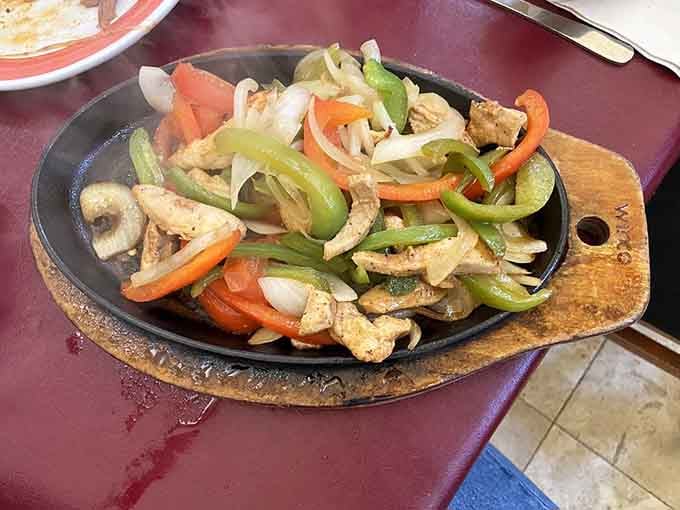 That sizzling skillet of chicken fajitas arrives like a locomotive, all steam and sizzle and irresistible aroma filling the air.