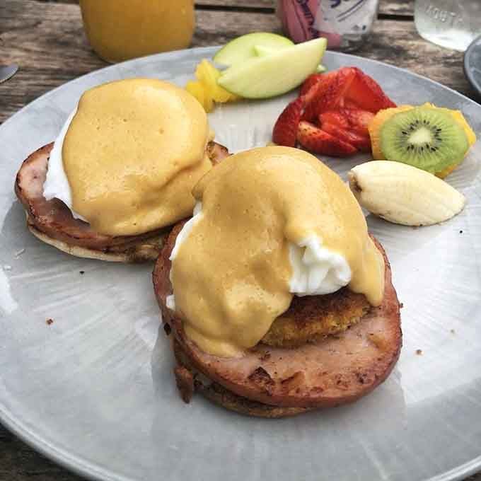 Eggs Benedict done right, with hollandaise so good it deserves its own fan club and fresh fruit.