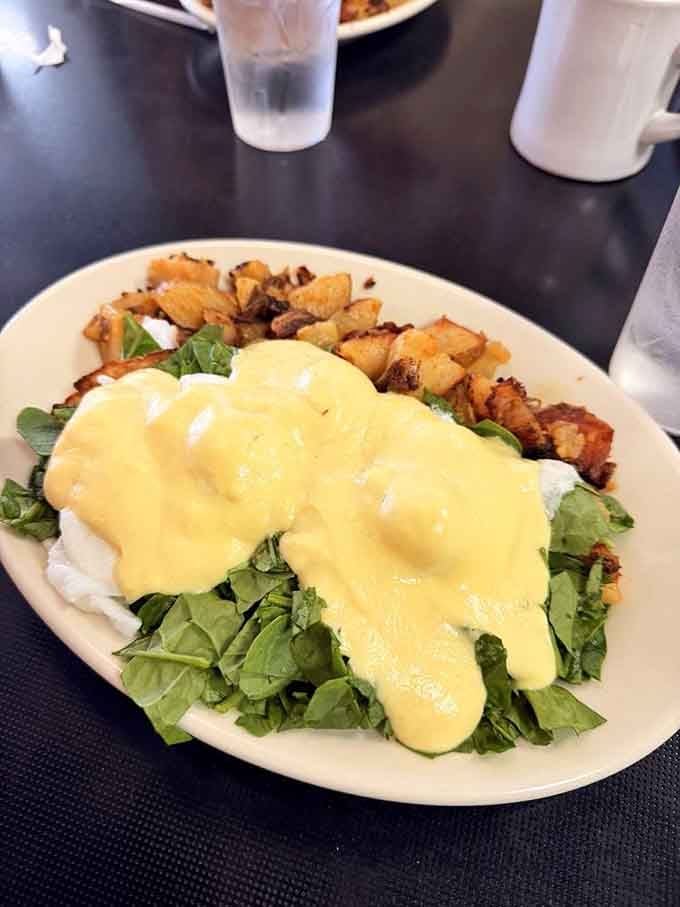 Eggs Benedict draped in hollandaise over greens and hash browns proves breakfast can be both elegant and hearty.