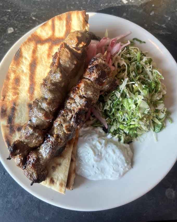 Charred lamb skewers with pickled onions and fresh greens bring Mediterranean flavors to Cambridge in one beautiful, savory presentation.