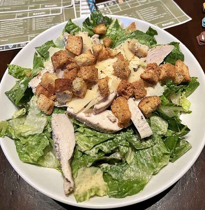 A Caesar salad piled high with chicken and croutons—the kind of substantial dish that fuels hours of gameplay.