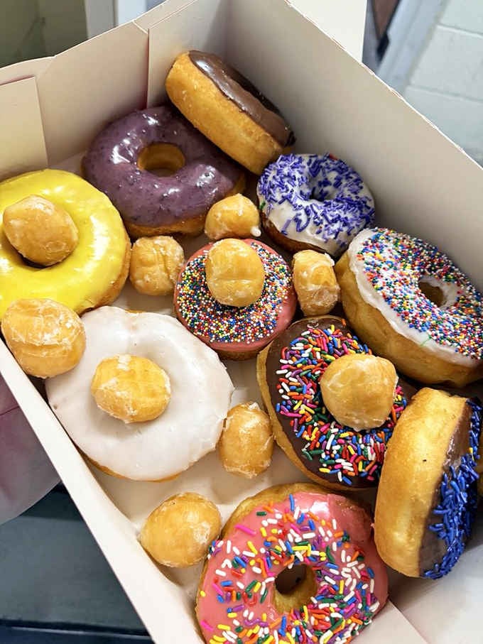 A mixed dozen that looks like a rainbow exploded in the best possible way, complete with donut holes as backup.