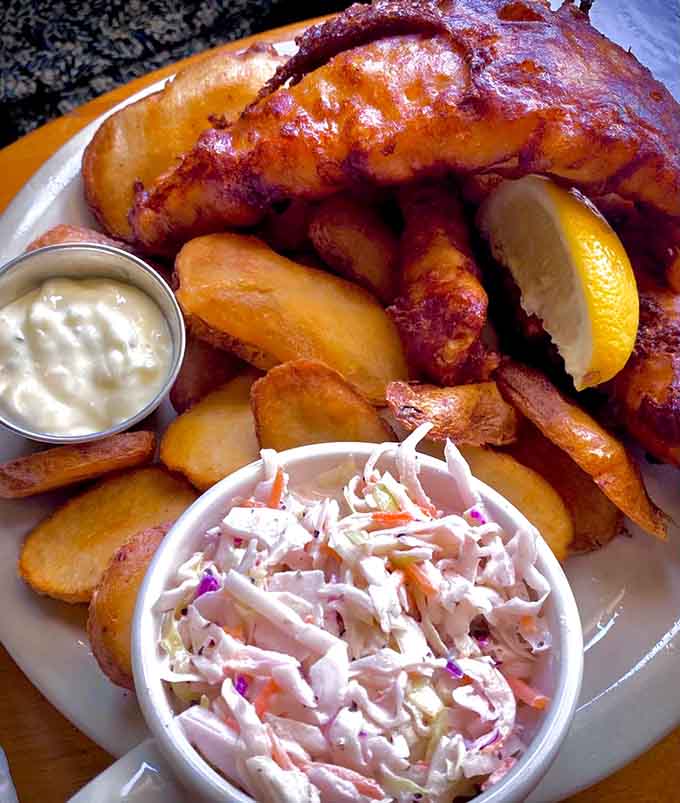 Golden, crispy fish with perfectly cooked chips and coleslaw: this is what fish and chips dreams are made of.