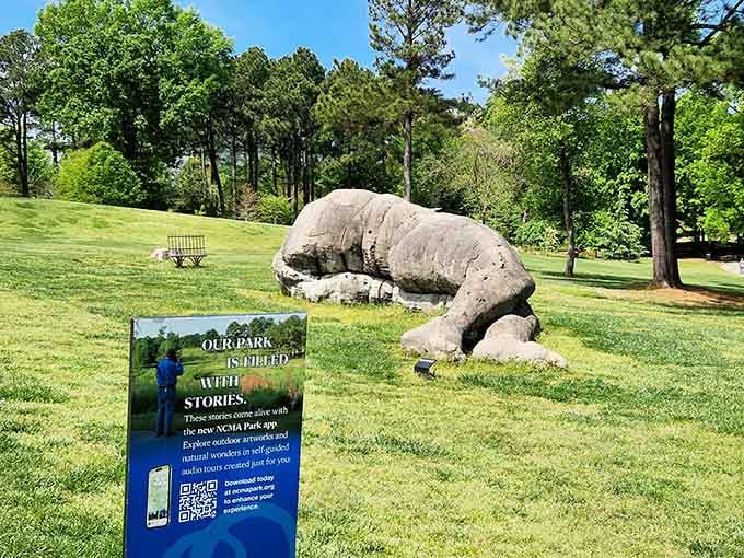 A giant stone creature rests peacefully in the grass, proving that even monumental art needs a good nap sometimes.