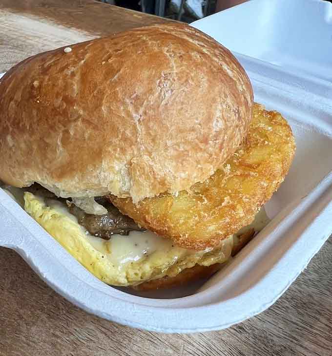 A golden hash brown patty nestled in a croissant with egg proves that breakfast engineering has reached its evolutionary peak.