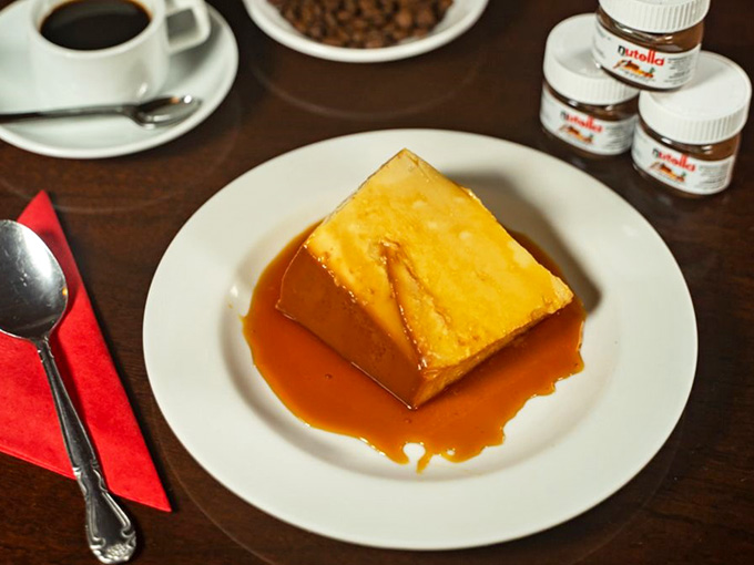 Golden flan swimming in caramel sauce that's basically liquid happiness poured over creamy perfection in dessert form.