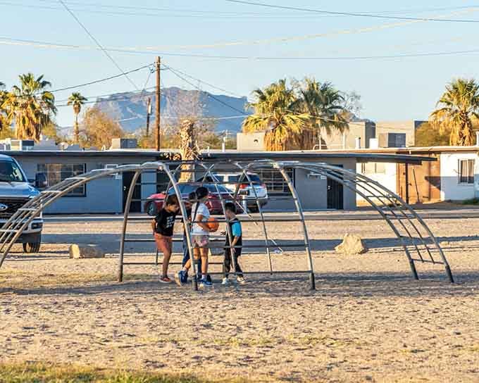 Simple playground equipment under desert palms where kids can be kids without needing WiFi passwords or charging stations nearby.