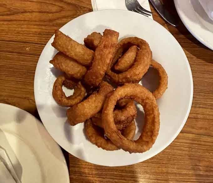 Golden onion rings piled high like edible architecture, crispy enough to hear the crunch from across the table.