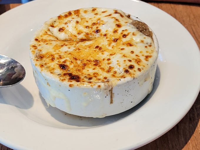 French onion soup arrives with a gloriously browned cheese cap that requires strategic spoon work to conquer.