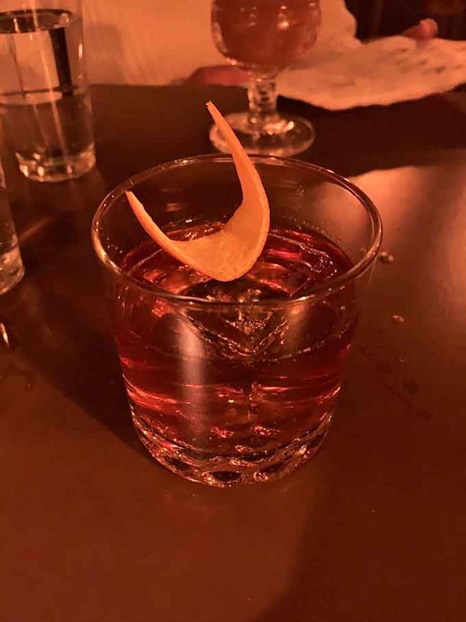 A perfectly crafted old fashioned with a citrus twist, glowing under moody lighting like a tiny sunset.
