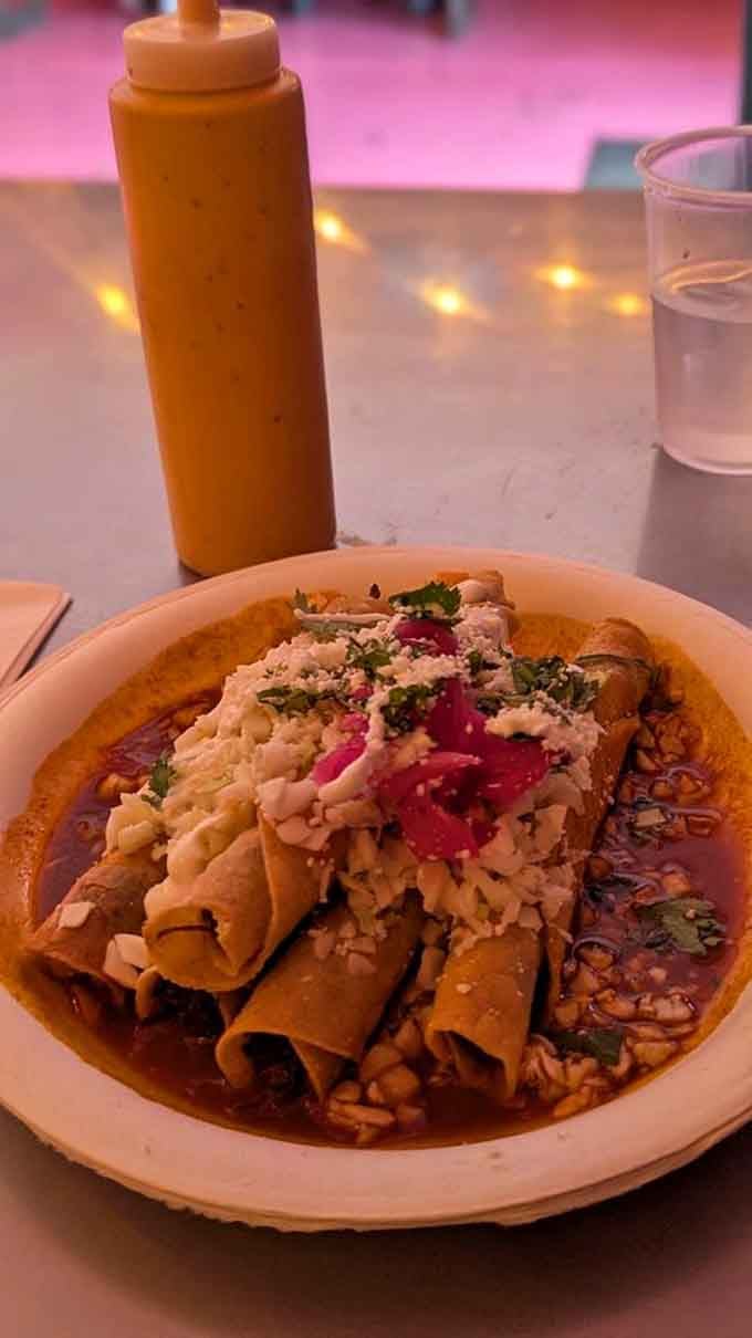 Golden rolled tacos swimming in sauce, topped with cheese and pickled vegetables, pure comfort in a bowl.