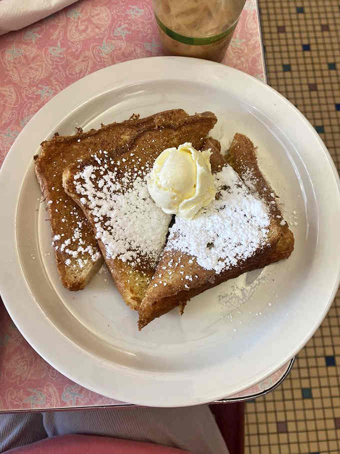 French toast dusted with powdered sugar and topped with butter: breakfast goals achieved in three golden slices.