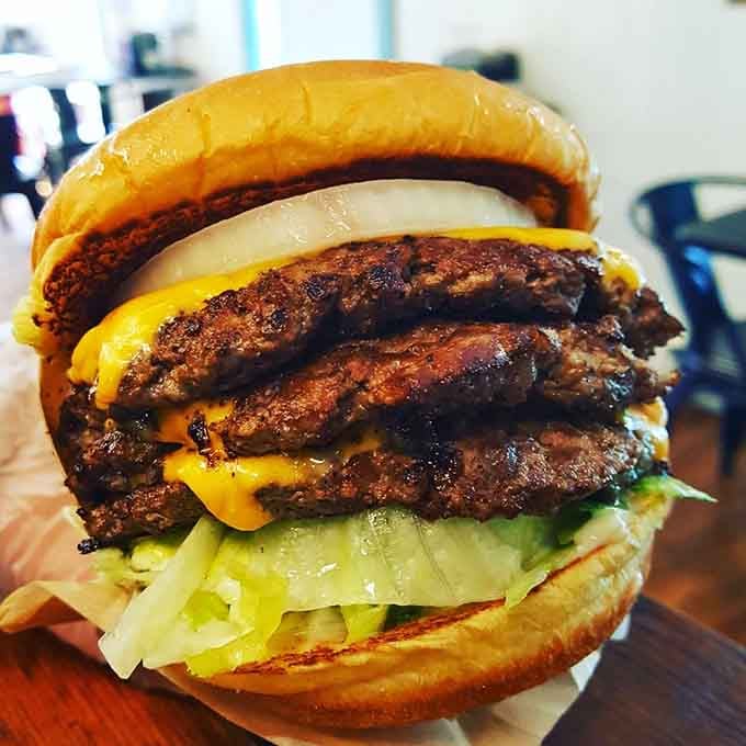 Three beef patties towering with cheese that's doing exactly what cheese should do: melting with reckless abandon.