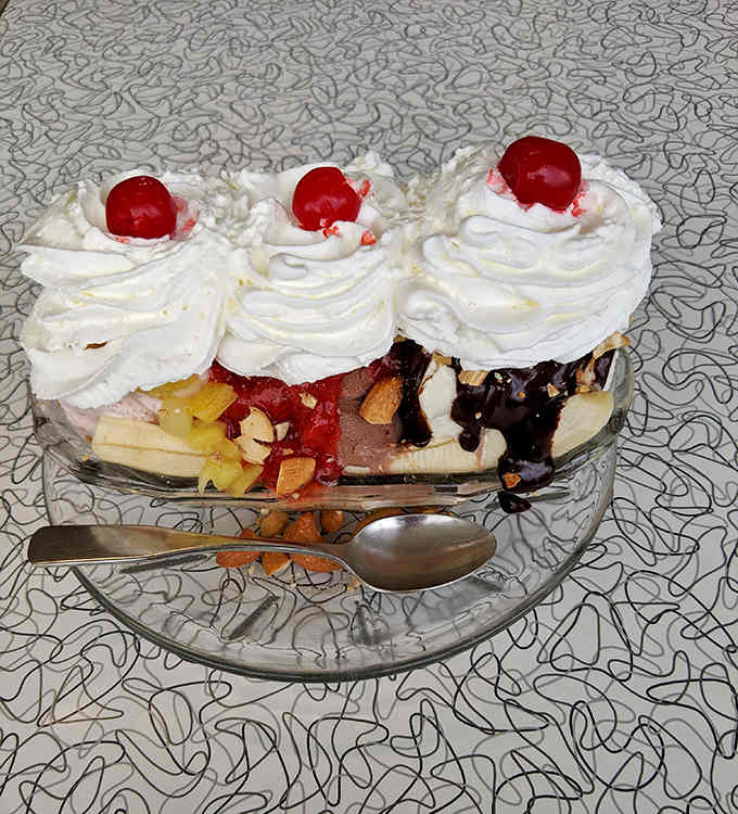 Three scoops, three cherries, and enough whipped cream to make your cardiologist schedule an intervention worth having.