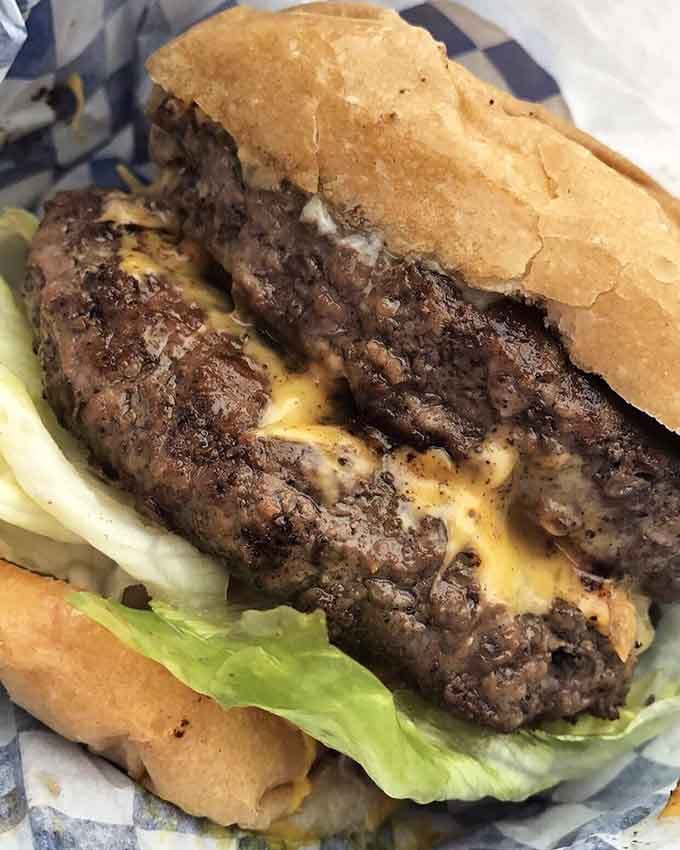 Look at those beautifully charred beef patties nestled between layers of melted cheese and fresh toppings.