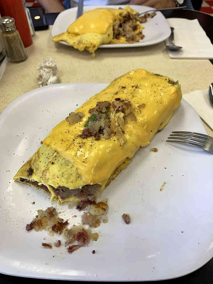 That golden omelette blanket wraps around its filling like it's protecting precious cargo, which it absolutely is.