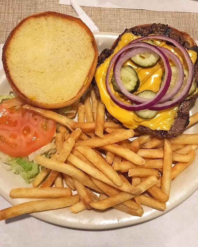 This burger comes loaded with pickles, onions, and melted cheese that cascades like a delicious dairy waterfall over perfectly seasoned beef.