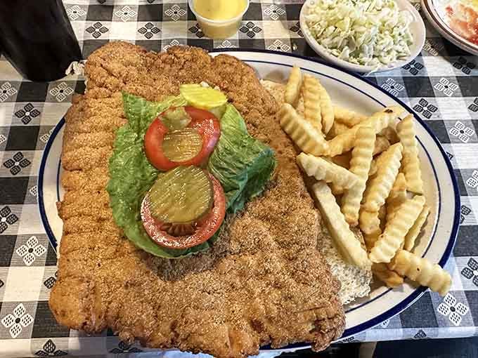 This golden-brown beauty extends beyond the plate's edge like it's trying to escape, and honestly, who could blame it?