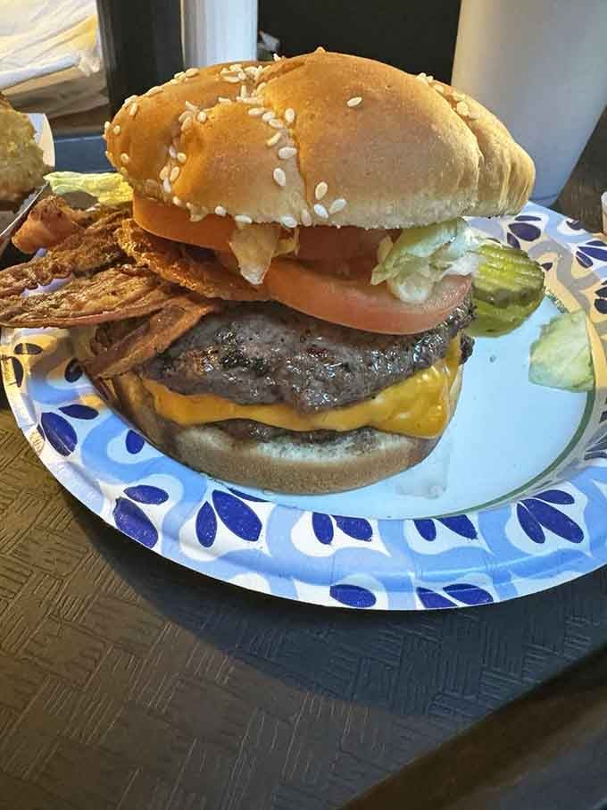 Behold the bacon cheeseburger in all its glory: charcoal-grilled perfection stacked high enough to require architectural planning before eating.