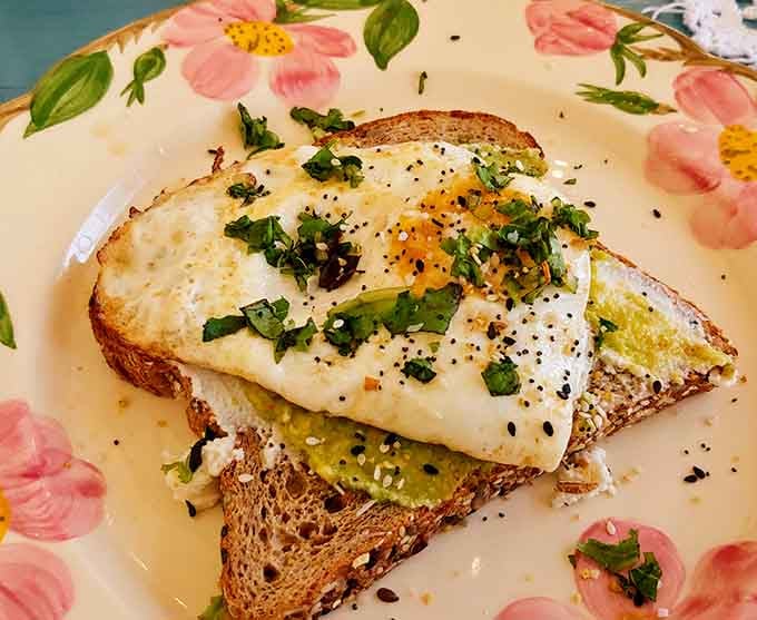 Avocado toast gets the Wonderland treatment with a perfectly fried egg, proving breakfast classics can wear fancy hats too.