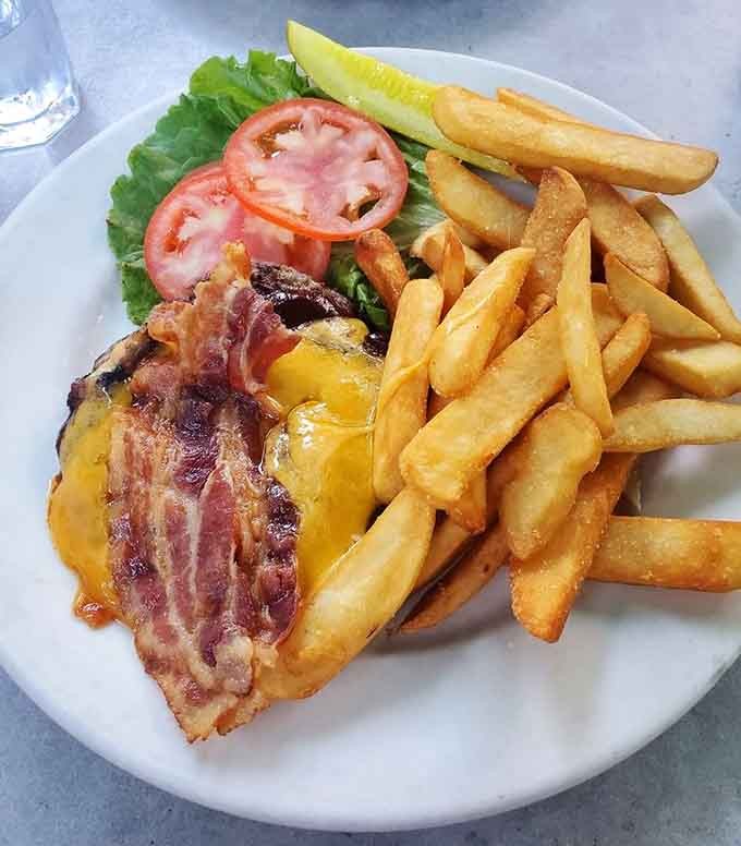 That bacon-wrapped burger with melted cheese is basically a hug in edible form, served with golden fries.