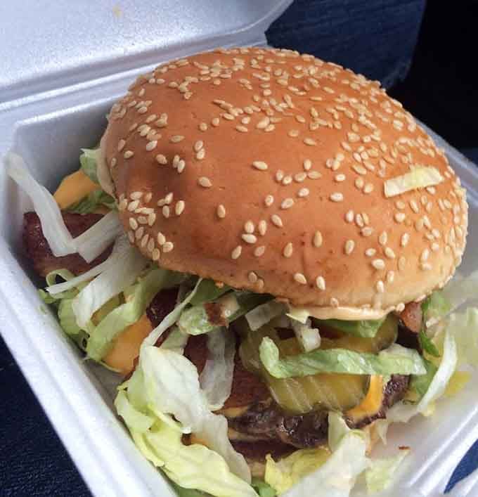 Sesame seed bun barely containing the chaos beneath: lettuce, tomato, pickles, and pure indulgence stacked high.