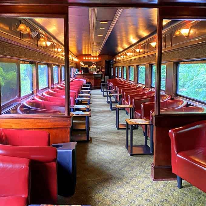 Inside the lounge car where red leather booths and warm lighting create the coziest rolling living room imaginable.