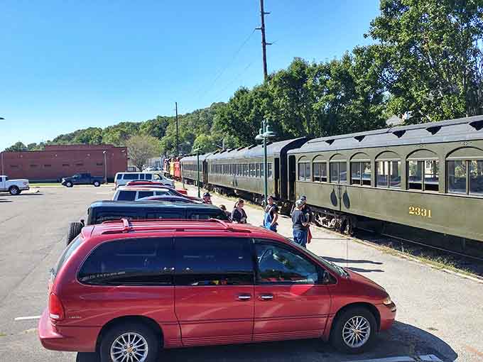 Modern minivans meet vintage trains in a parking lot where two centuries shake hands every weekend.