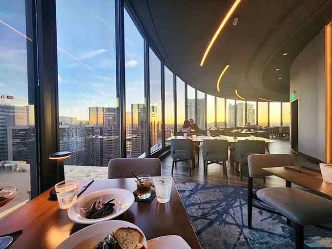 Golden hour through floor-to-ceiling windows transforms your meal into a slowly rotating panorama of the glittering city below.