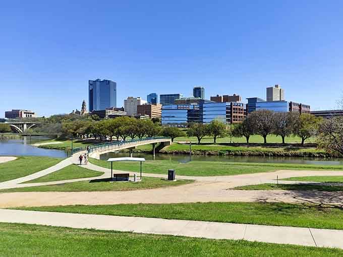Green riverside parks stretch toward the modern skyline, offering peaceful walking paths where nature and city life shake hands and smile.