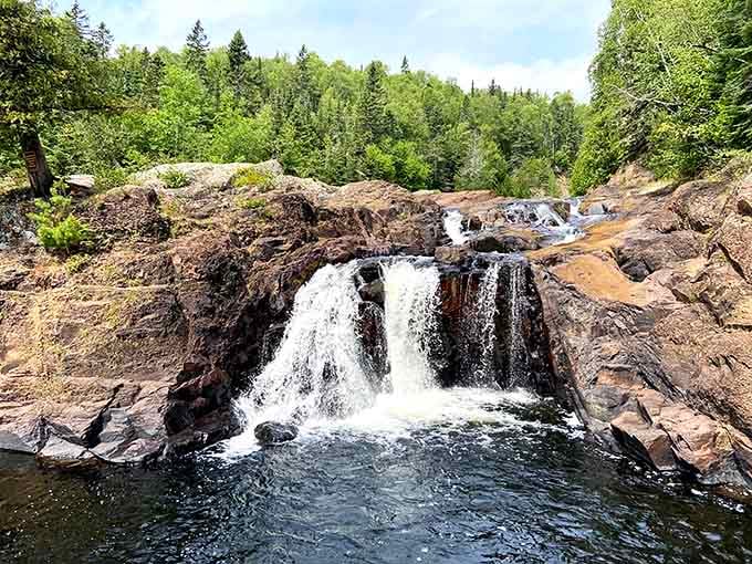 Water crashes over ancient rock in powerful cascades that echo through the forest.