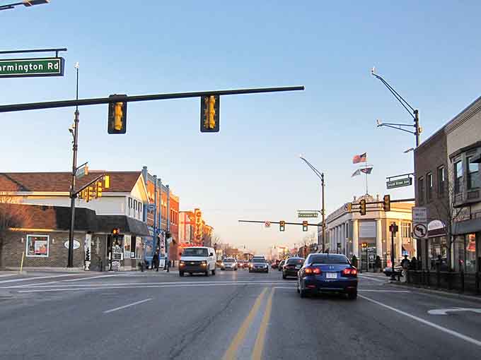 Golden hour light bathes the main street as traffic flows gently past, capturing that perfect moment between workday and evening relaxation.