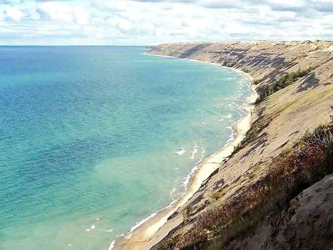 These towering sand cliffs meet turquoise water in a view that belongs on a postcard from somewhere much farther away.