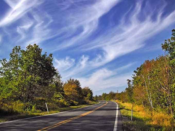 Those wild cloud patterns overhead make this quiet country road look like heaven's putting on a show.