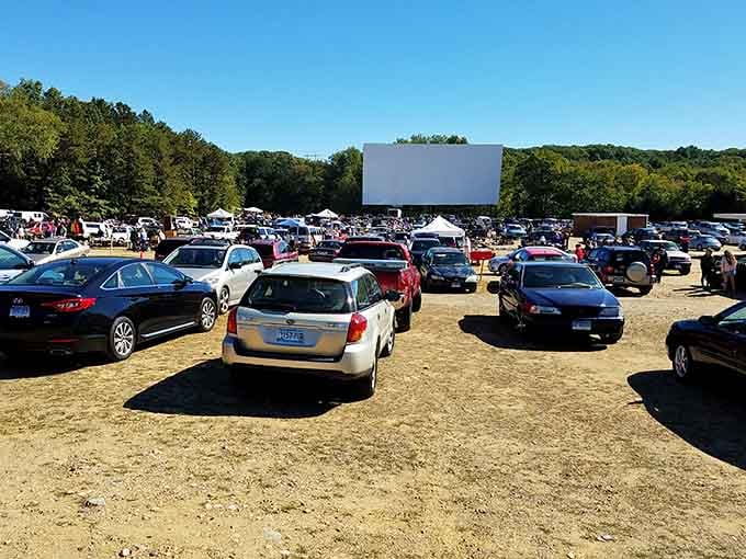 Classic drive-in screen towers over parked cars, where shopping and movies create the perfect weekend double feature.