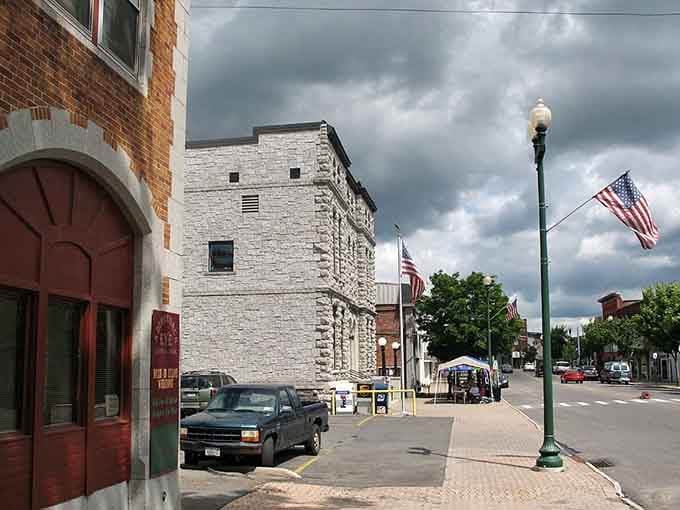 Storm clouds gather dramatically over downtown streets where American flags wave proudly despite the threatening weather rolling in overhead.
