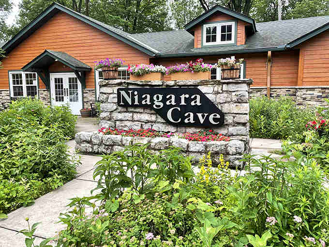 Flowers frame the welcoming entrance to underground chambers where a 60-foot waterfall thunders in complete darkness below.