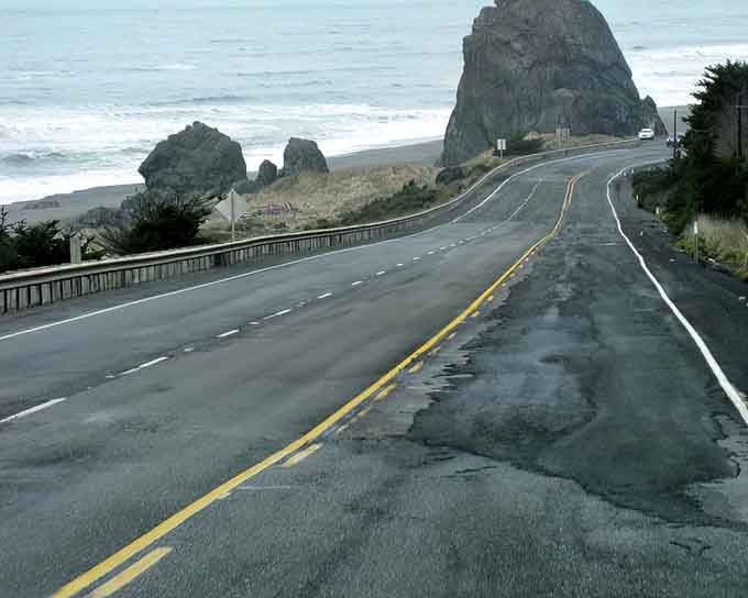 Haystack Rock rises from the misty shore as the coastal highway curves past this Pacific icon.