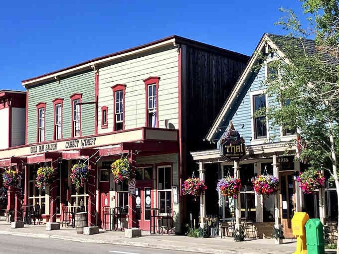 Hanging flower baskets and vintage storefronts create Main Street charm that Gunsmoke would envy completely.
