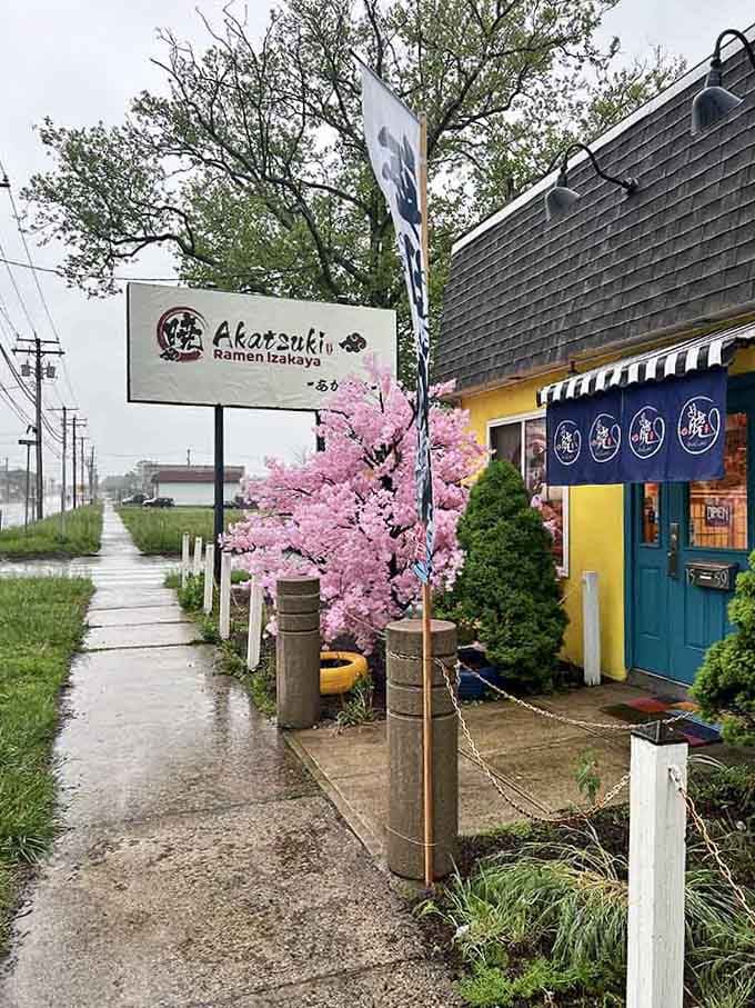 That traditional blue noren curtain and roadside signage promise bowls of steaming comfort that warm both body and soul.