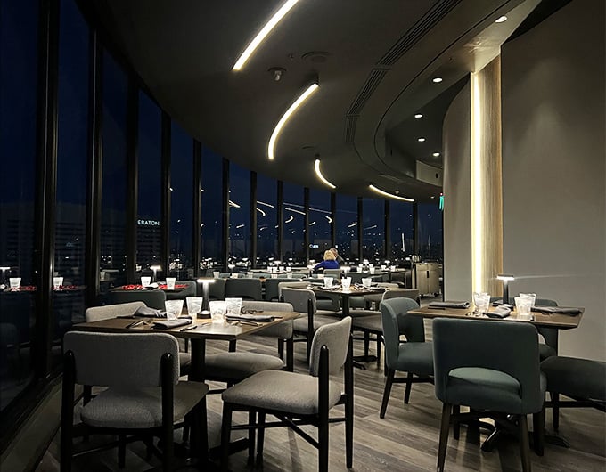 As darkness falls, the curved dining room glows softly while Phoenix sparkles like scattered diamonds far beneath your table.