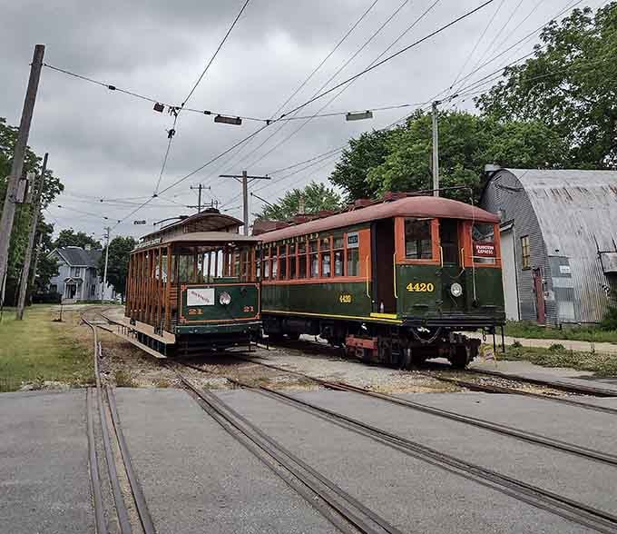 Two classic trolleys meet at the intersection, their overhead wires creating geometric patterns against the cloudy sky.