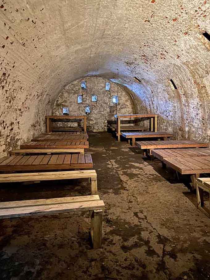 Inside these vaulted casemates, wooden bunks line damp stone walls where Revolutionary War soldiers once huddled against the cold darkness.