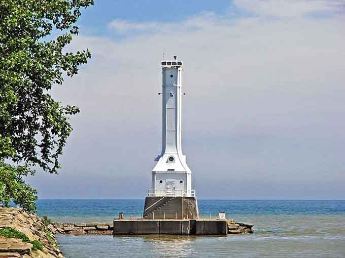 Framed by shoreline greenery, this striking white lighthouse appears almost ethereal against the turquoise water.