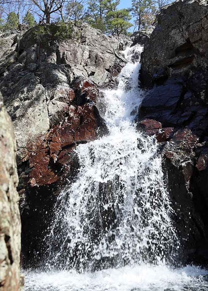 The falls cascade down volcanic stone in tiers, each level more vibrant than the last in nature's palette.